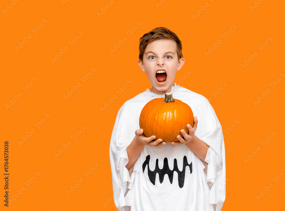 Young boy dressed white ghost costume holds pumpkin and screams with ...