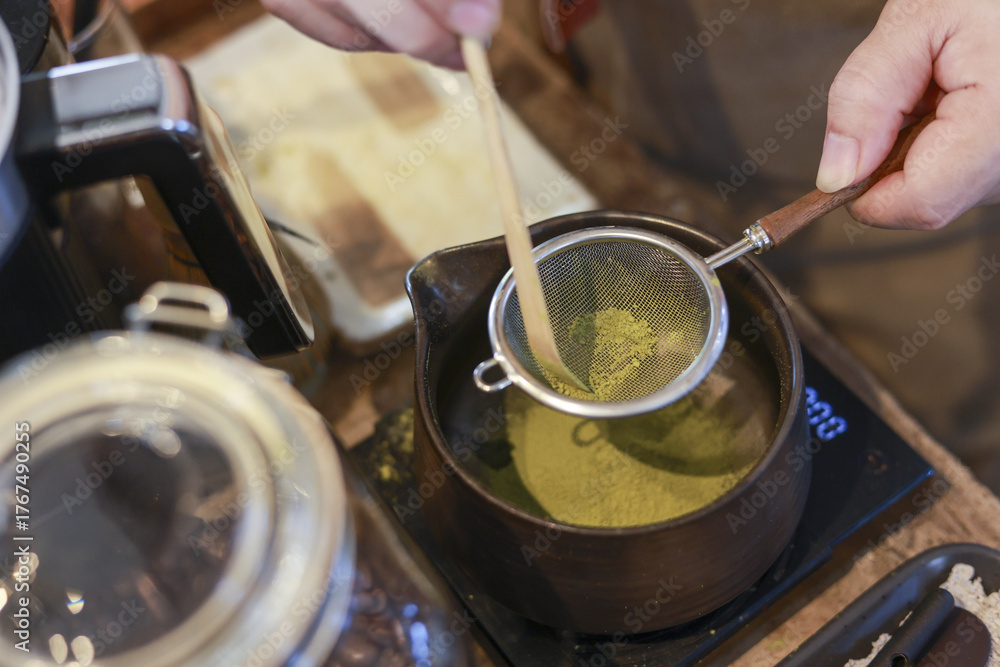 Focused barista making an authentic matcha green tea drink, sifting ...