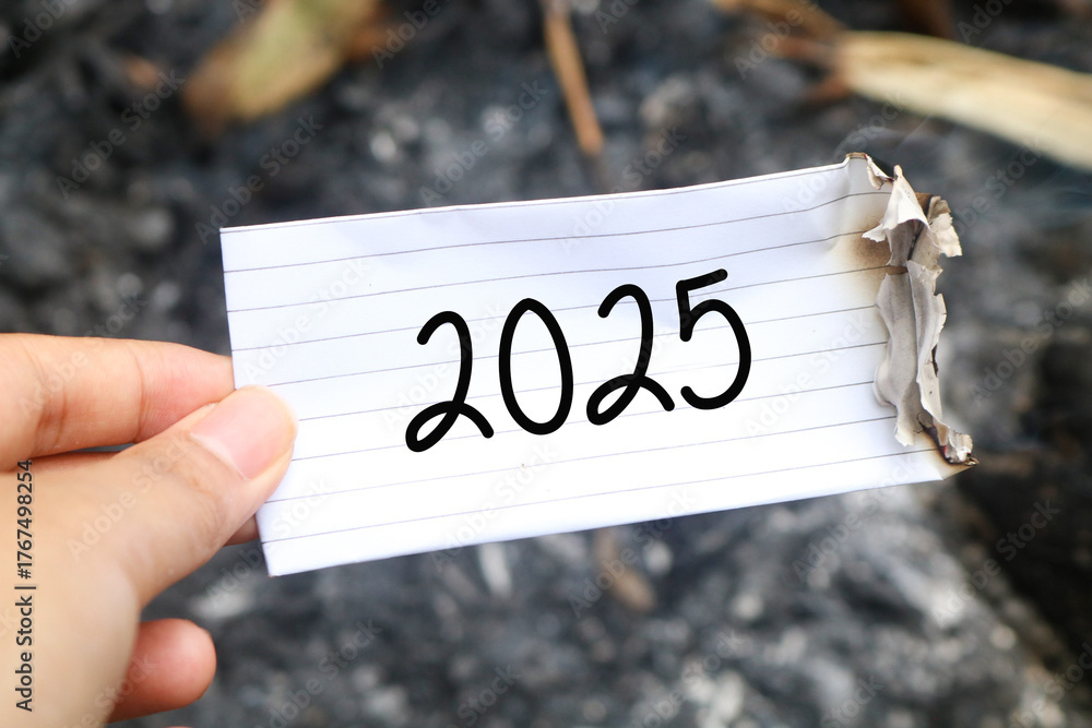 Hand holding a half-burnt note with 2025 written on it. Goodbye 2025 ...