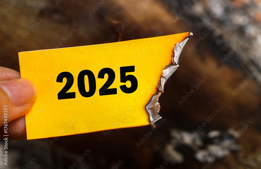 Zdjęcie bez tantiem: Hand holding a half-burnt note with 2025 written ...