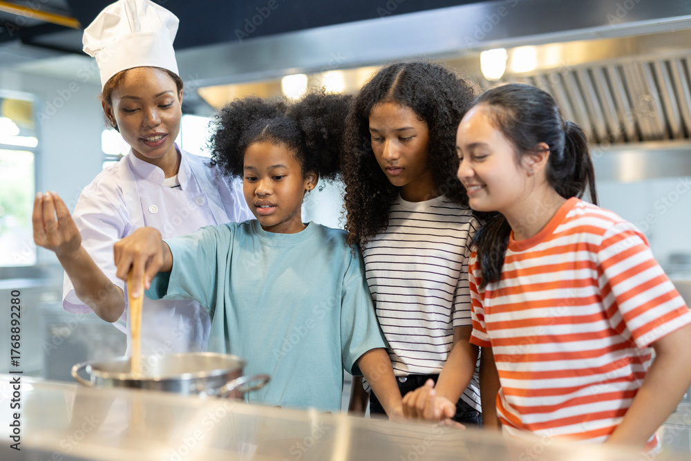Professional female chef teaching diverse group of kids how to cook in ...