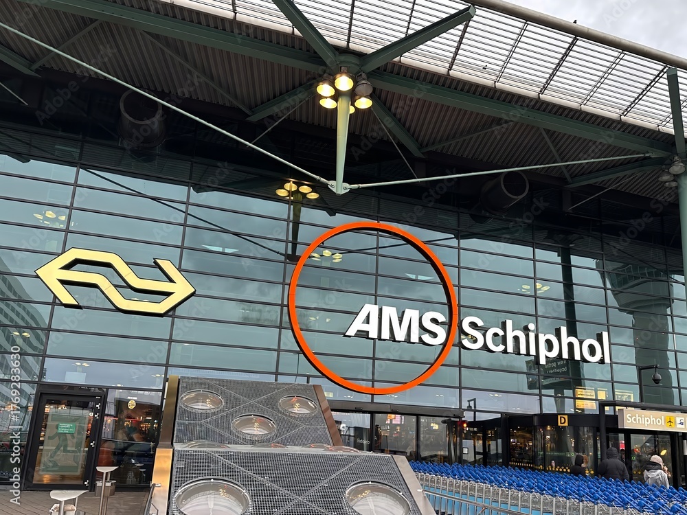 New AMS Schiphol Airport logo on modern glass airport building and baggage trolleys 26 October ...