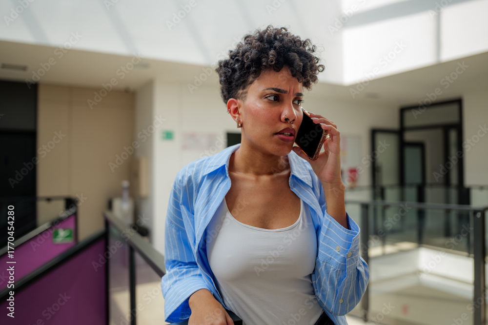 Young latin american university student is making a serious phone call ...