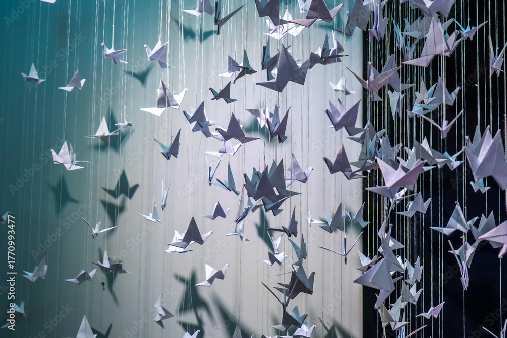 paper origami birds tied to strings hanging in air against a black ...
