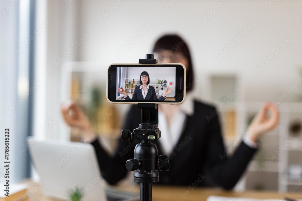 Caucasian woman in office environment recording meditation video at ...
