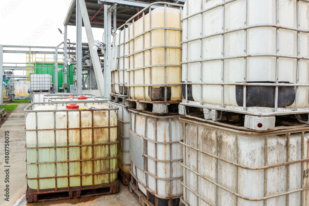 Industrial bulk containers (IBCs) with liquids, stacked outdoors at a ...