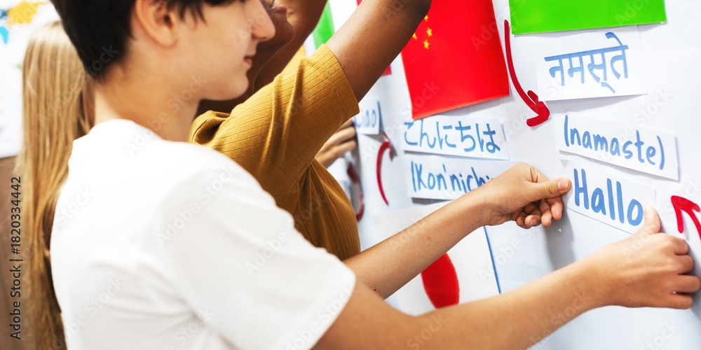 Students placing multilingual greeting cards on a board. Diverse group ...