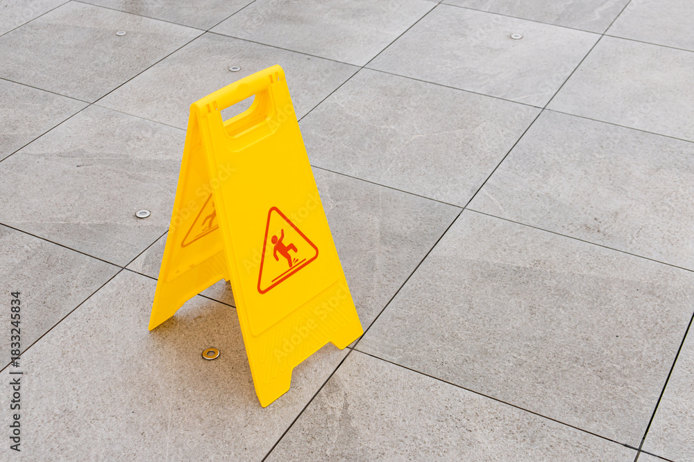 Yellow a frame warning sign placed on wet tiled floor, alerting people ...