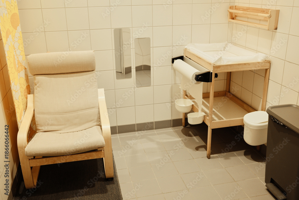 Clean baby care room with a changing table, chair, paper dispenser, and ...