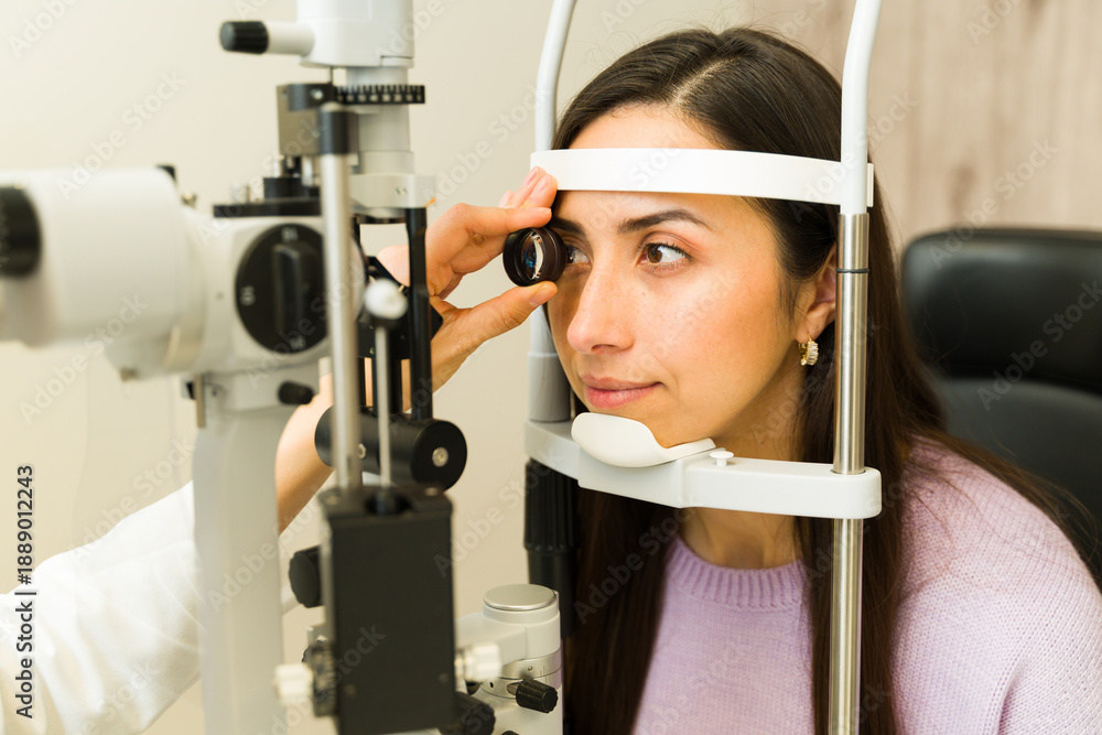 Ophthalmologist examining woman's eye with slit lamp for vision care ...
