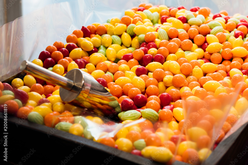 Assorted fruit shaped gummy candies and chewy gum in a container ...