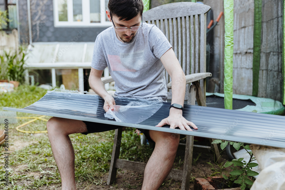 Horizontal portrait of a young man unpacking a sheet of metal from a ...