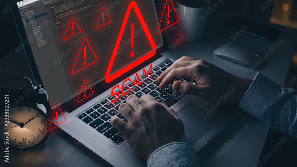 Warning about a scam message on a laptop with alarming symbols at night ...
