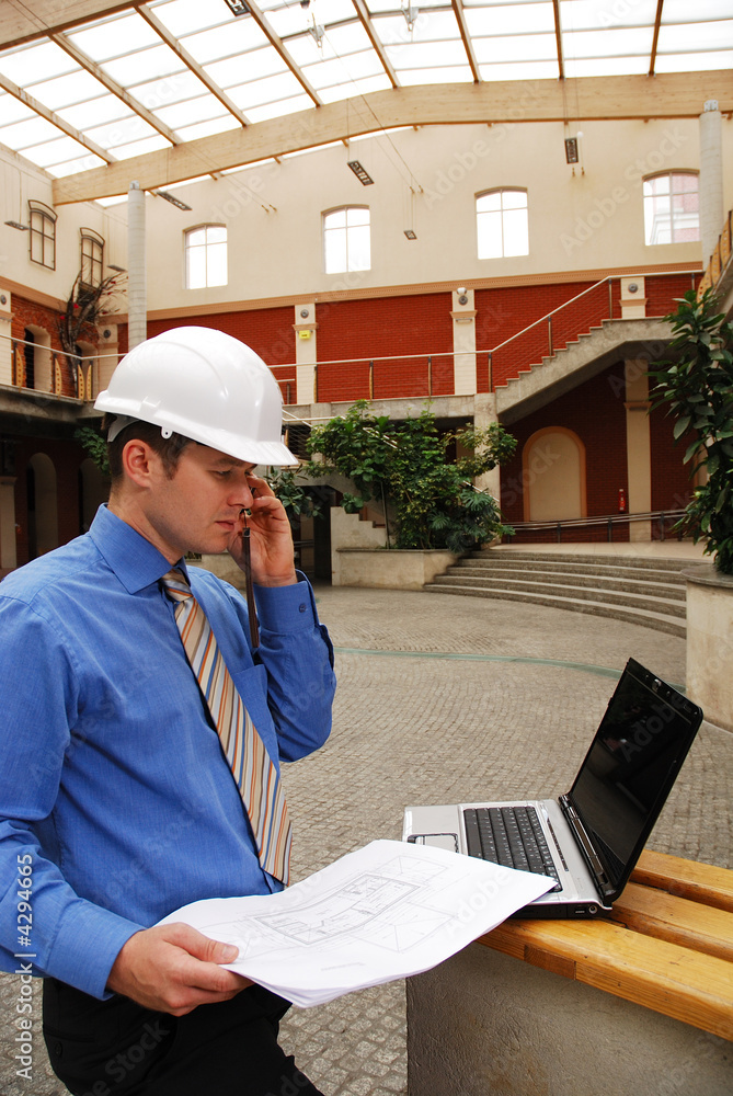 contractor in hardhat calling by phone and work with laptop Stock 写真 ...