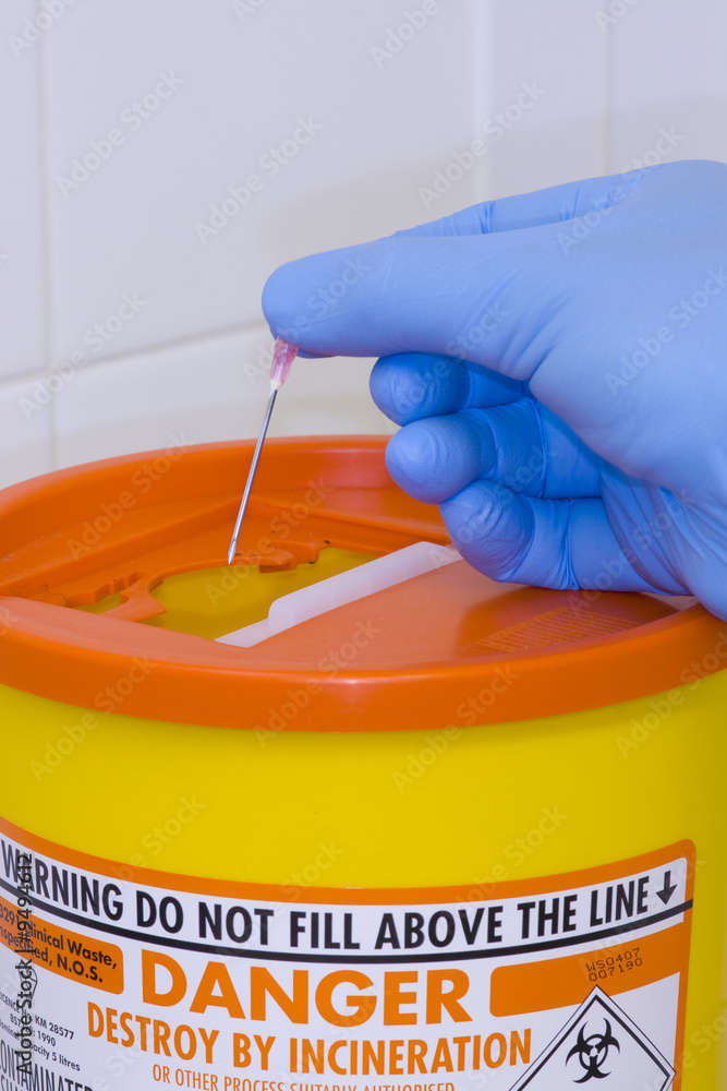 Safe disposal of a needle into a sharps container Stock Photo | Adobe Stock