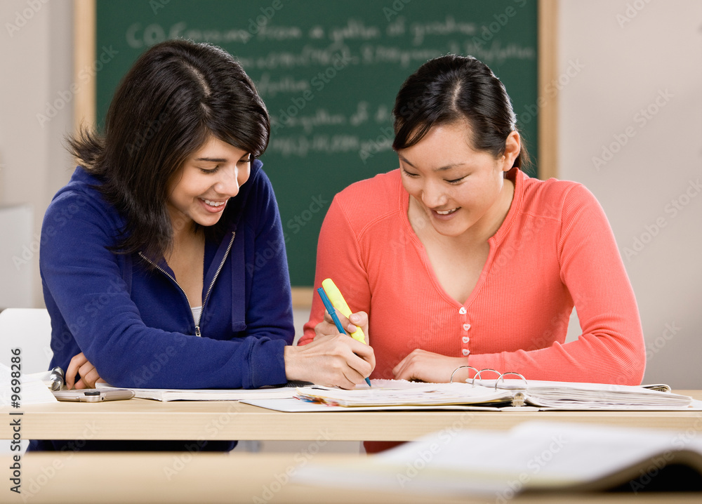 Student with text books helping friend do homework in classroom Stock ...