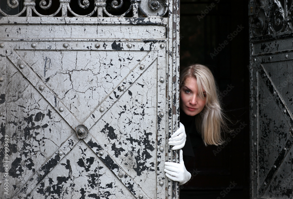 Beautiful woman looking looking out of dark vintage gate Stock Photo ...