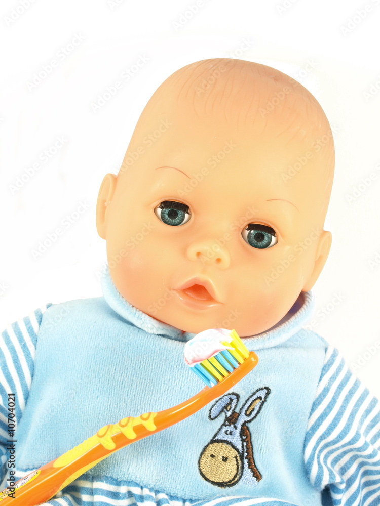 A baby doll brushing teeth. Stock Photo | Adobe Stock