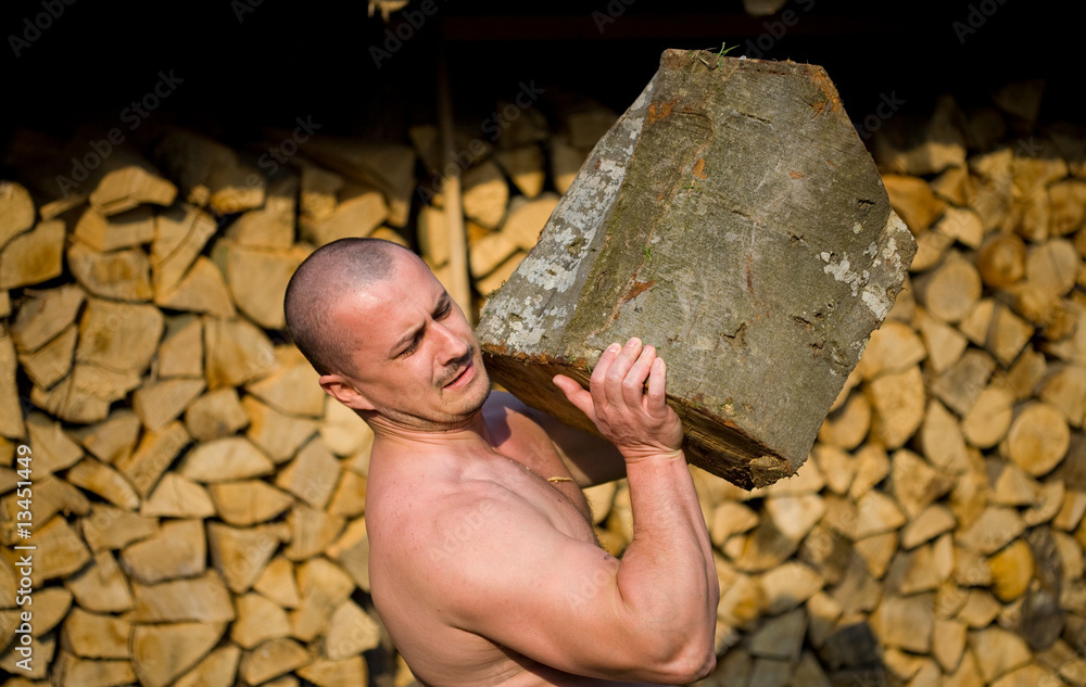 Strong man lifting a huge log, outdoor scene Stock Photo | Adobe Stock