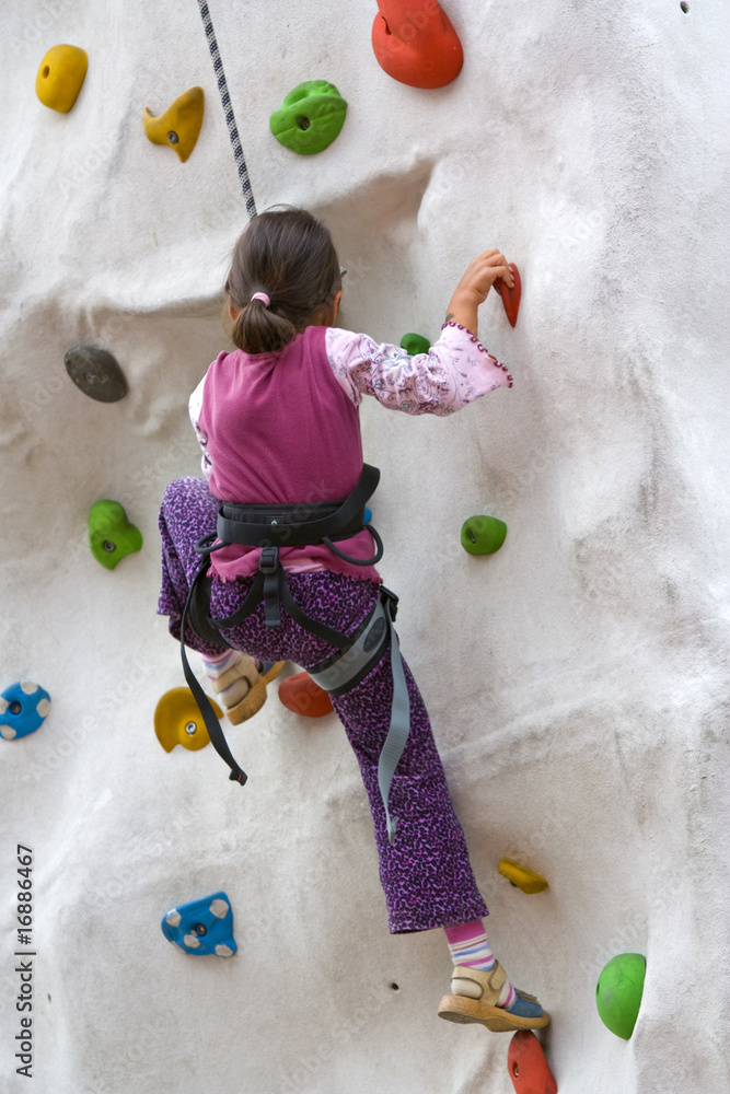 Kind beim Klettern an einer Kletterwand Stock-Foto | Adobe Stock