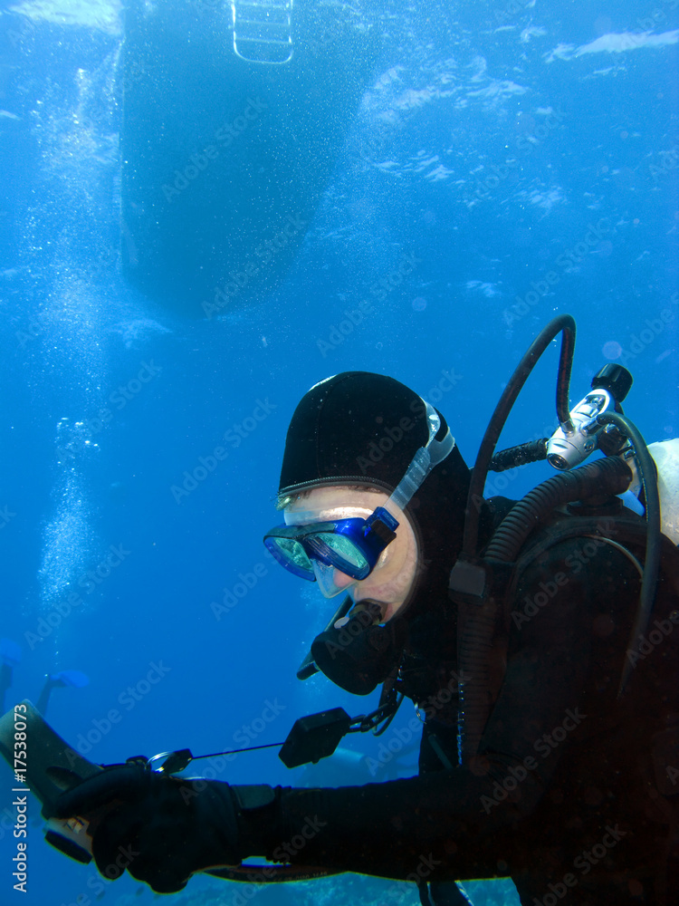 Scuba Diver Checking Gauges under the Boat Stock Photo | Adobe Stock