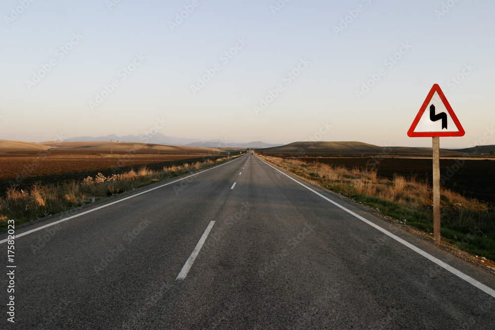 carretera recta con señal de curva peligrosa Stock Photo | Adobe Stock