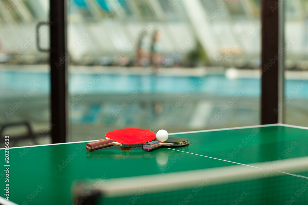 Table tennis rackets and ball swimmig pool in the background Stock ...