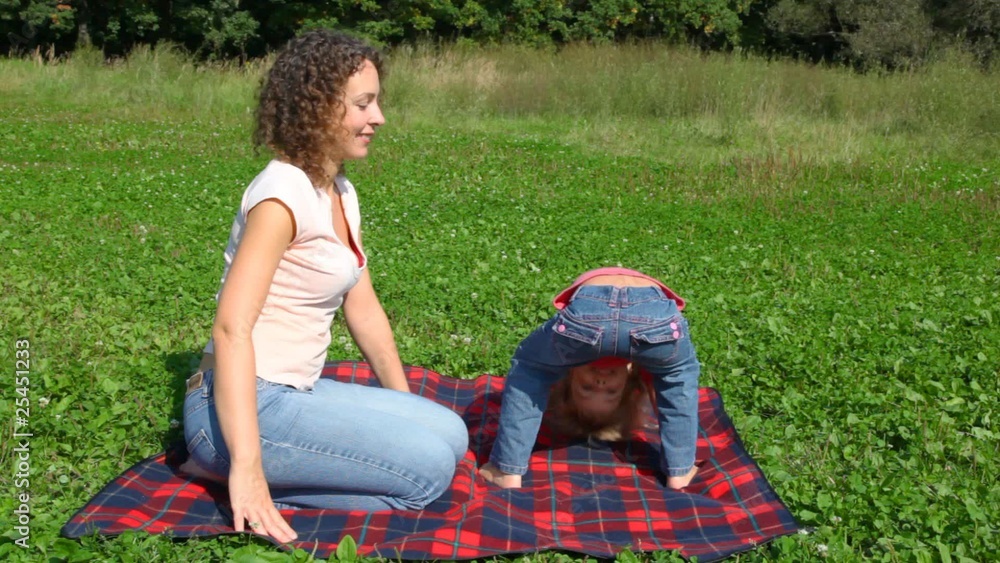 girl looks upside down between her legs and woman in summer park Stock ...