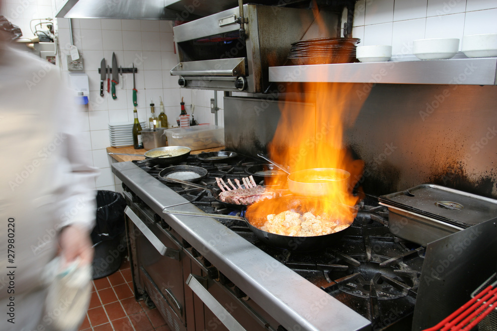 Meat cooking in the pan, flamed, restaurant kitchen, cook is moving ...