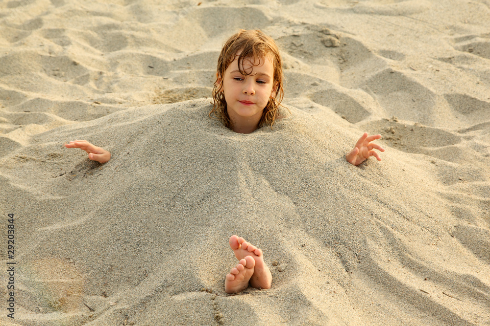 girl after swimming is buried in sand on beach Stock Photo | Adobe Stock