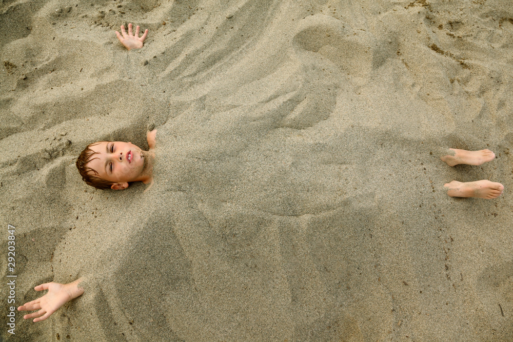 boy after swimming is buried in sand on beach Stock Photo | Adobe Stock