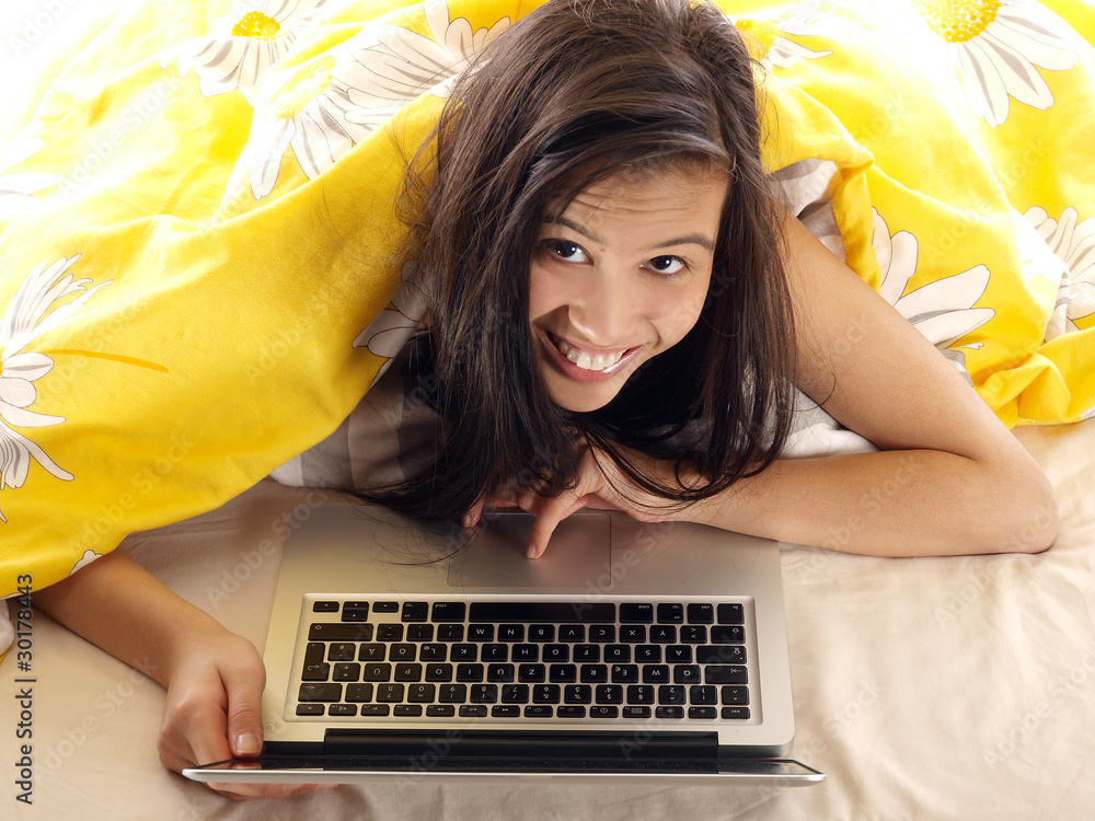 smiling girl lying in bed with a computer notebook Stock Photo | Adobe ...