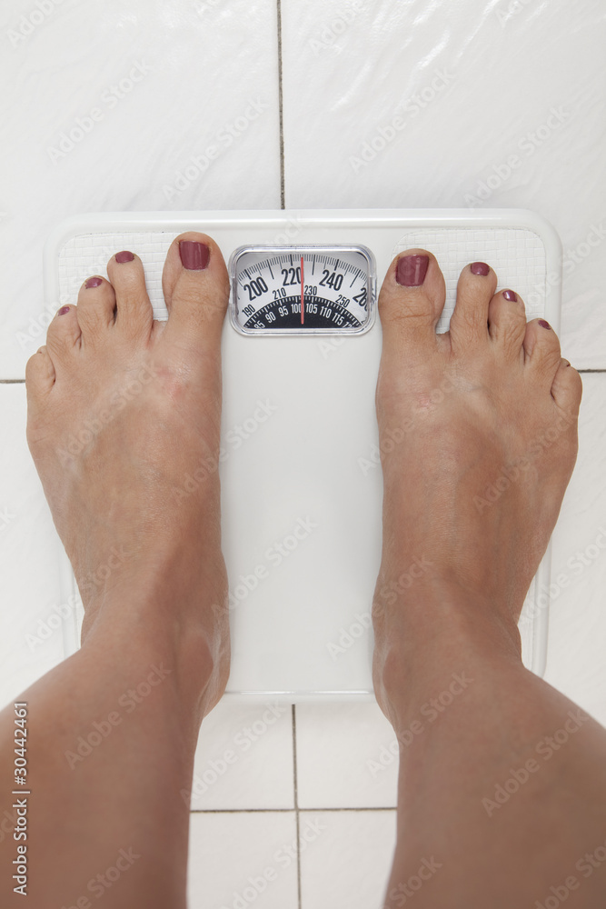 Overweight woman looking at weigh scale Stock Photo | Adobe Stock