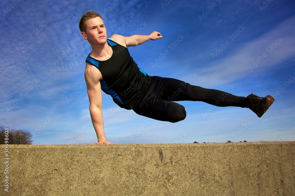 Young man jumping over wall on obstacle course Stock Photo | Adobe Stock