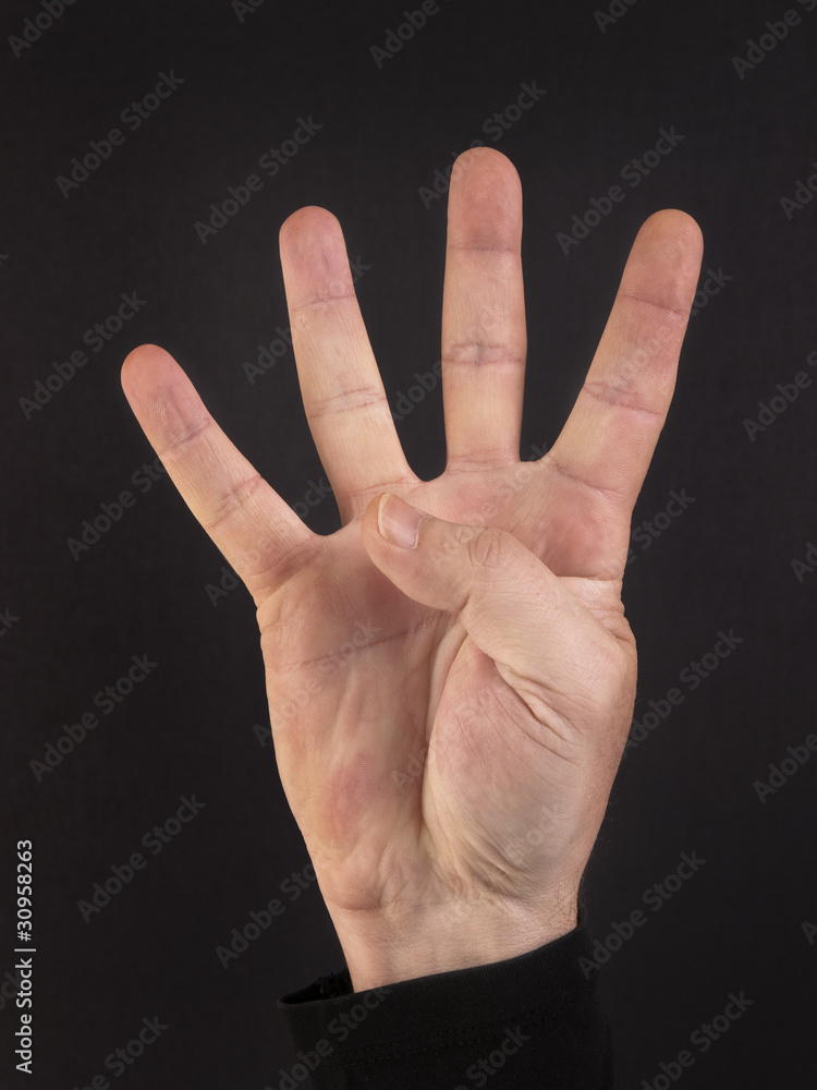 Mano de hombre formando el número cuatro con la mano sobre un fondo negro. Vista de frente y de ...