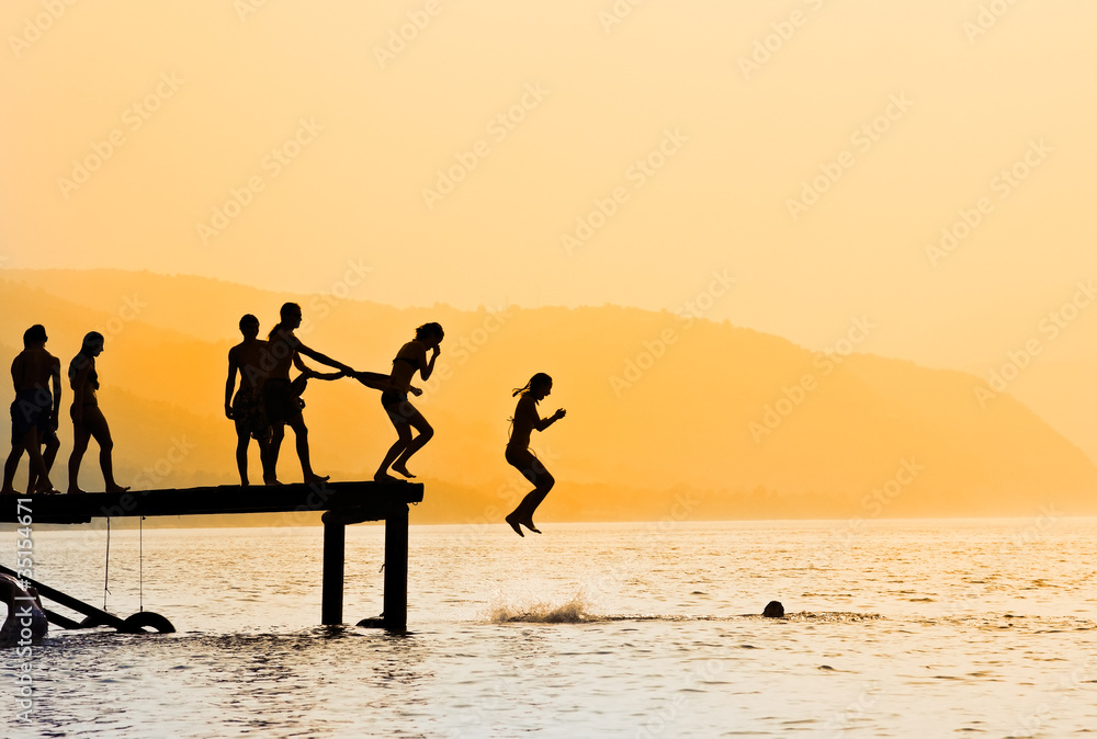 kids jumping off dock at sunset Stock Photo | Adobe Stock