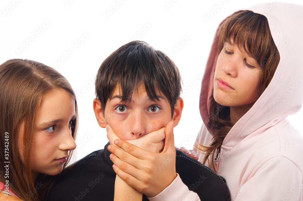 Two girls harrasing frightened boy Stock Photo | Adobe Stock