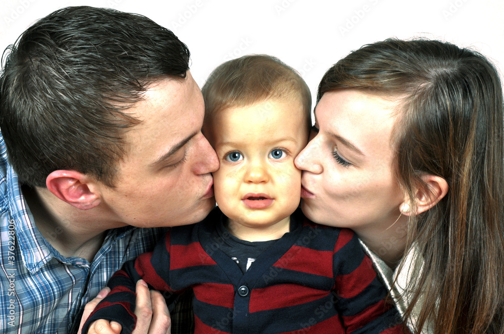 Stockfoto Familienglück: Das kleine Kind wird von den Eltern geküsst ...
