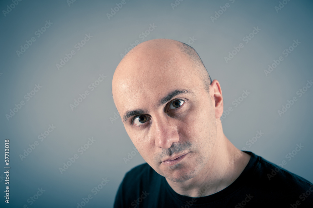 Bald man with fierce expression. Blue background. Stock Photo | Adobe Stock
