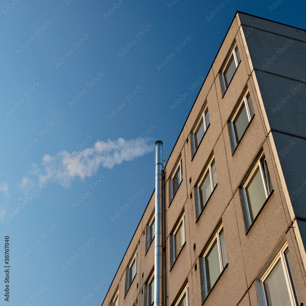 smoke/flue gases going out of a chimney by an apartment building Stock ...