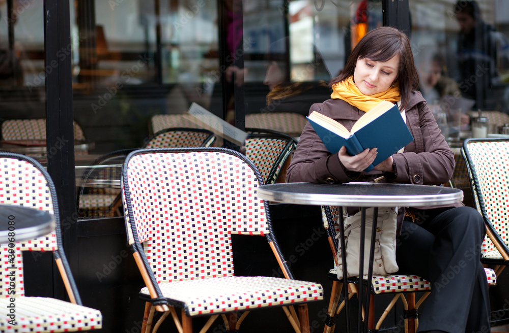 Beautiful young girl reading a book in Parisian street cafe Stock Photo ...