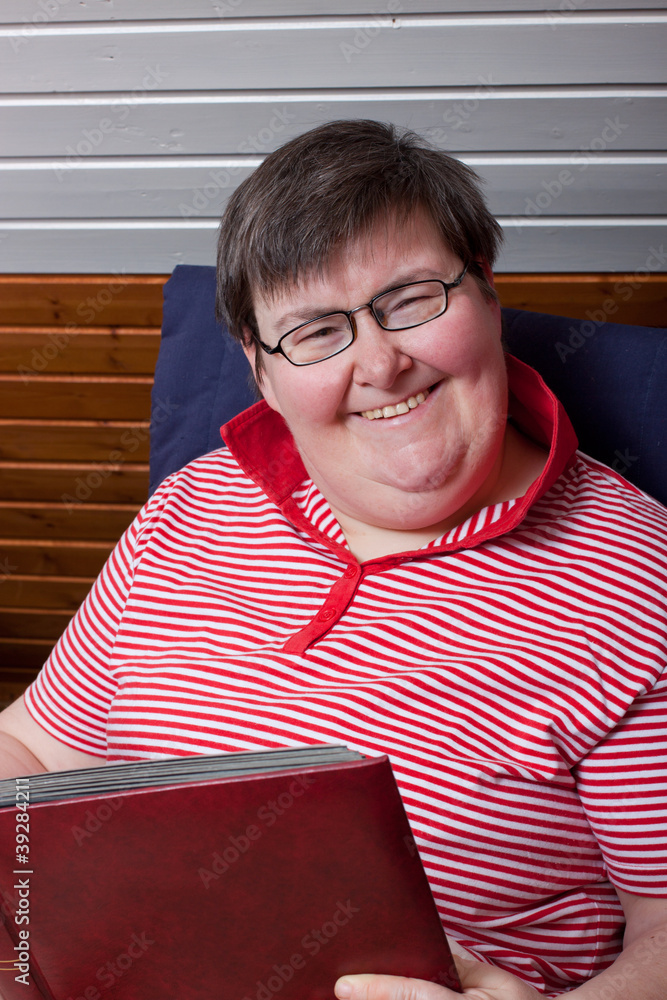 Geistig behinderte Frau liegt im Sessel und liest Stock-Foto | Adobe Stock
