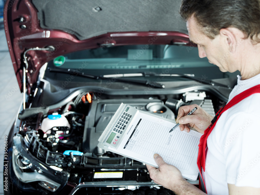 Motor mechanic in front engine bay writing a quotation Stock Photo ...