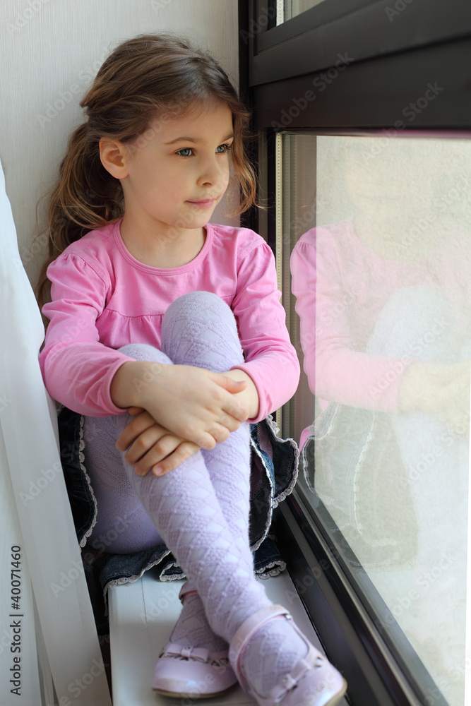 Little beautiful girl sits on windowsill and looks out window Stock ...