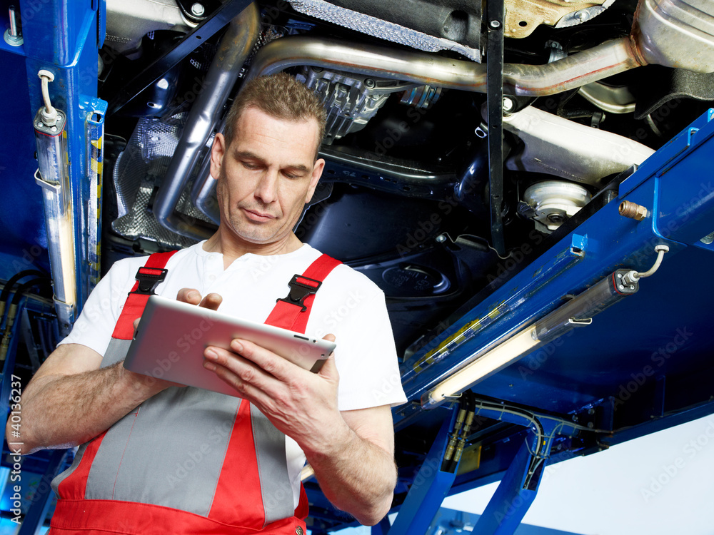 Motor mechanic works under the service lift with his touchpad Stock ...
