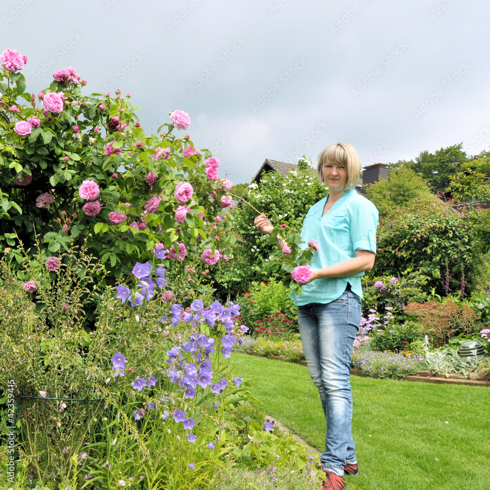 Frau im Garten mit Rosenstrauch Stock-Foto | Adobe Stock