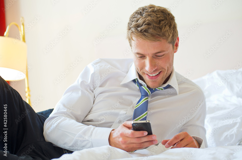 Mann mit Handy auf Bett Stock-Foto | Adobe Stock