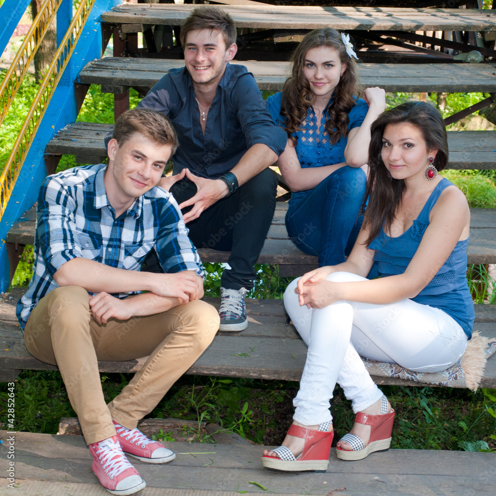 Four happy teenagers two boys and two girls sitting on stairs Stock ...