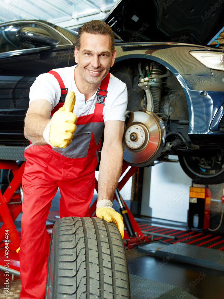 Motor mechanic shows thumb up for tyre fitting with new alu rim Stock ...
