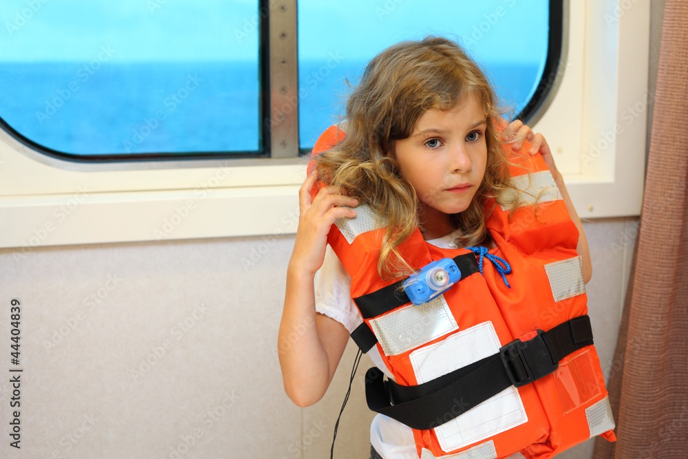 Sad little girl dressed in life jacket stands near window Stock Photo ...